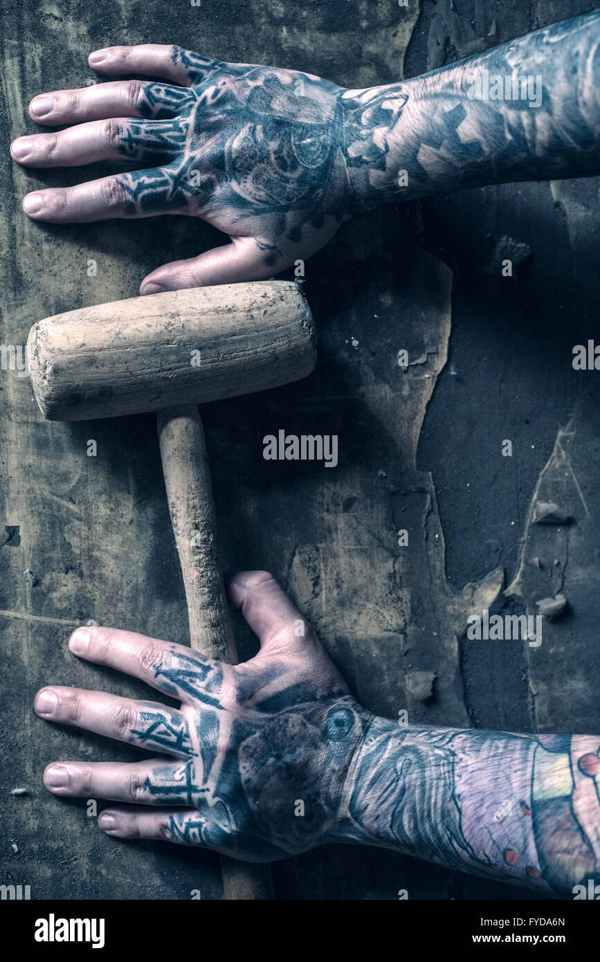 Hammer in the tattoed hands Stock Photo - Alamy