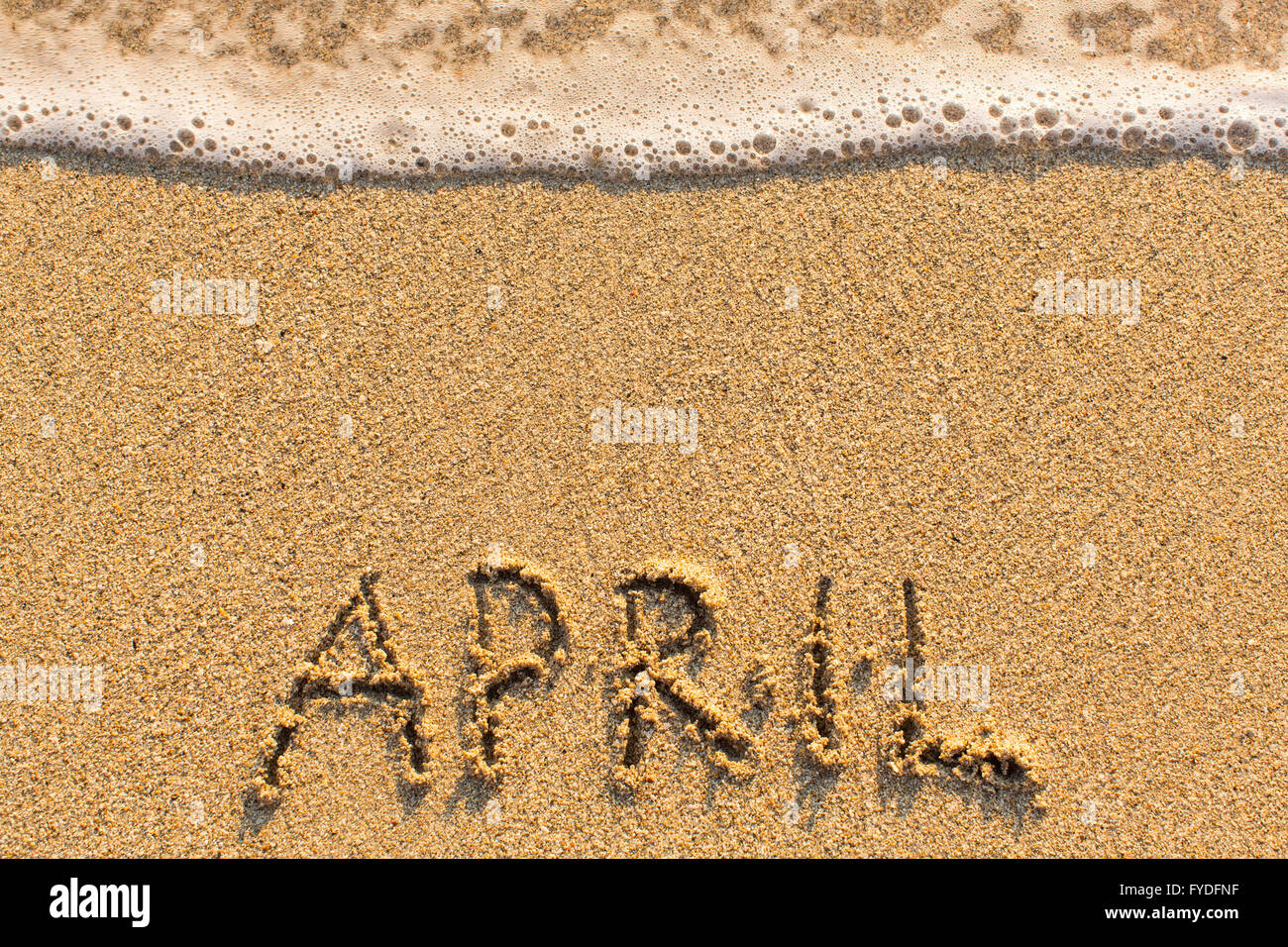 April - word drawn on the sand beach with the soft wave. Months series ...