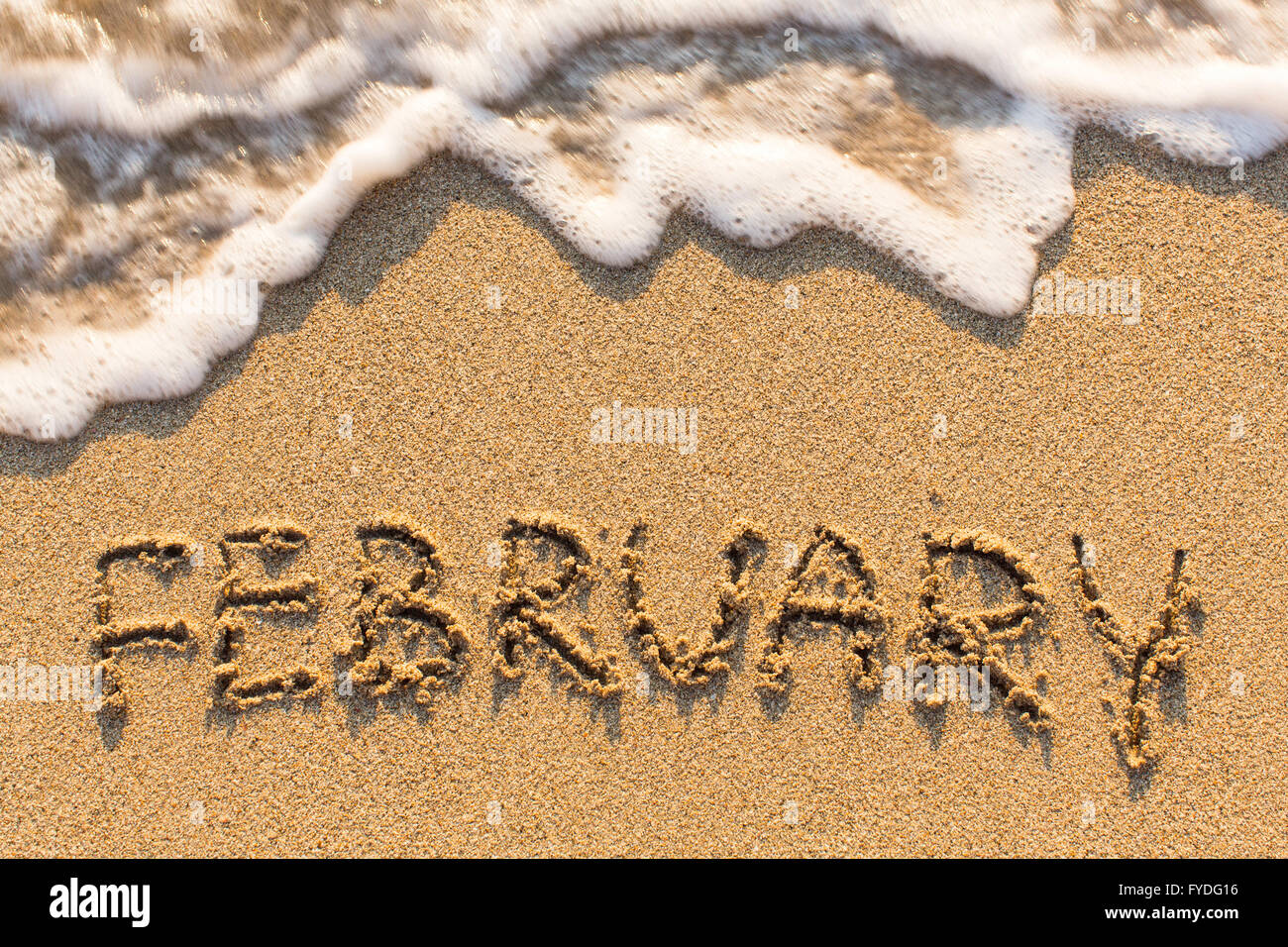 February - word drawn on the sand beach with the soft wave. Months ...