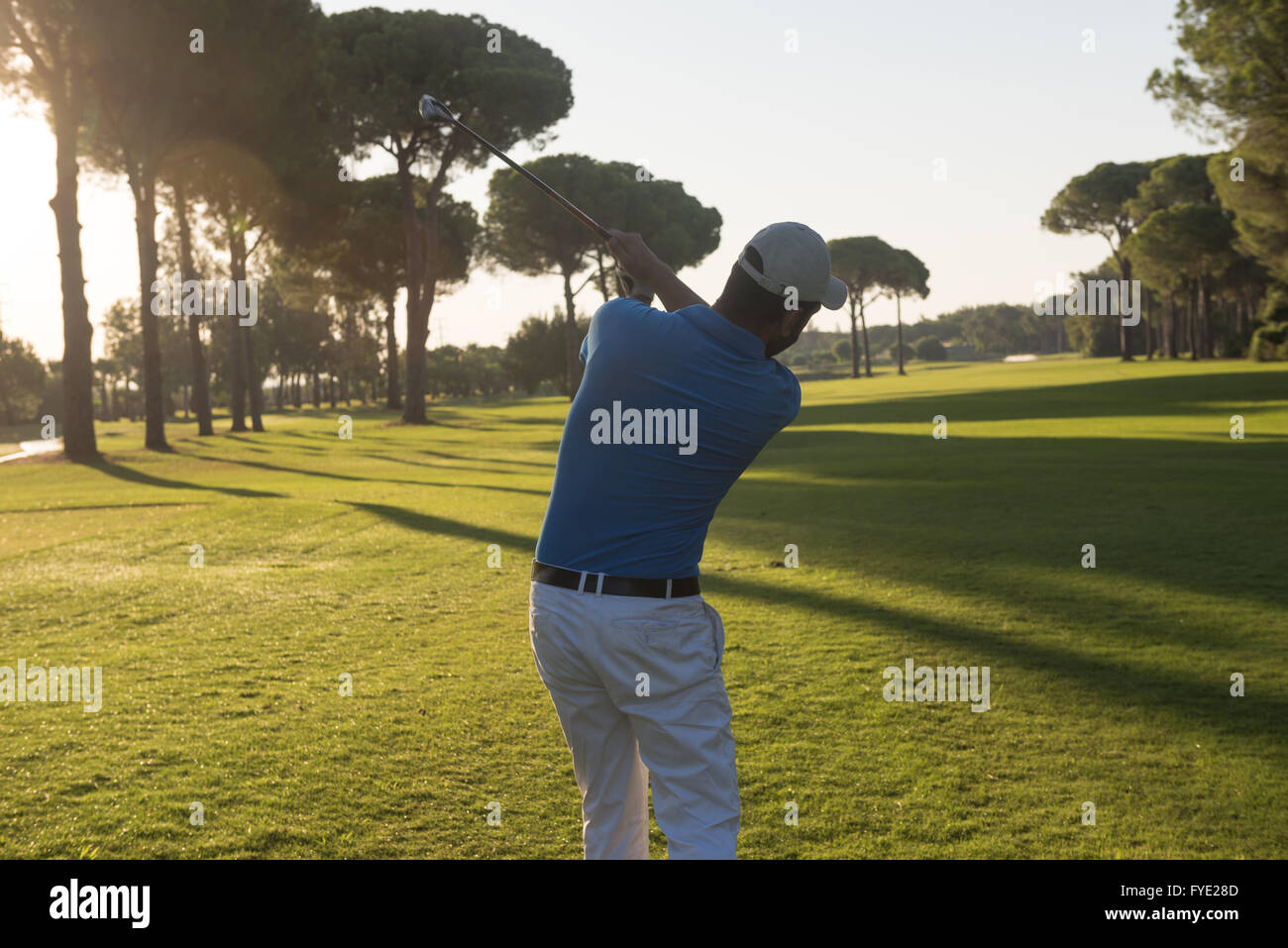 handsome sporty man, golf player hitting shot with club on course at ...