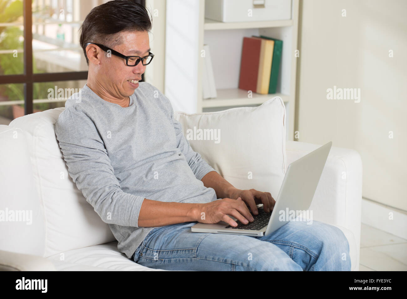 Man in living room with laptop smiling Stock Photo - Alamy