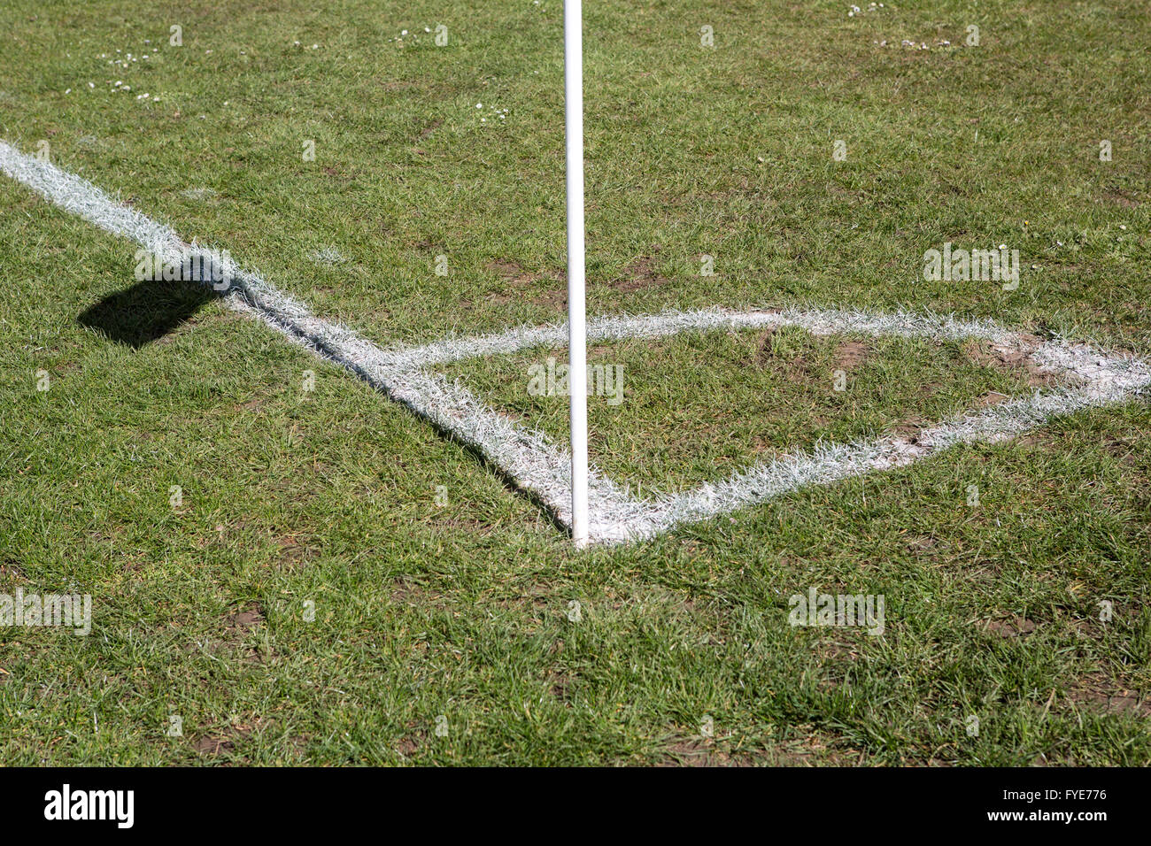 A corner flag casting a shadow over white lines on a football pitch ...