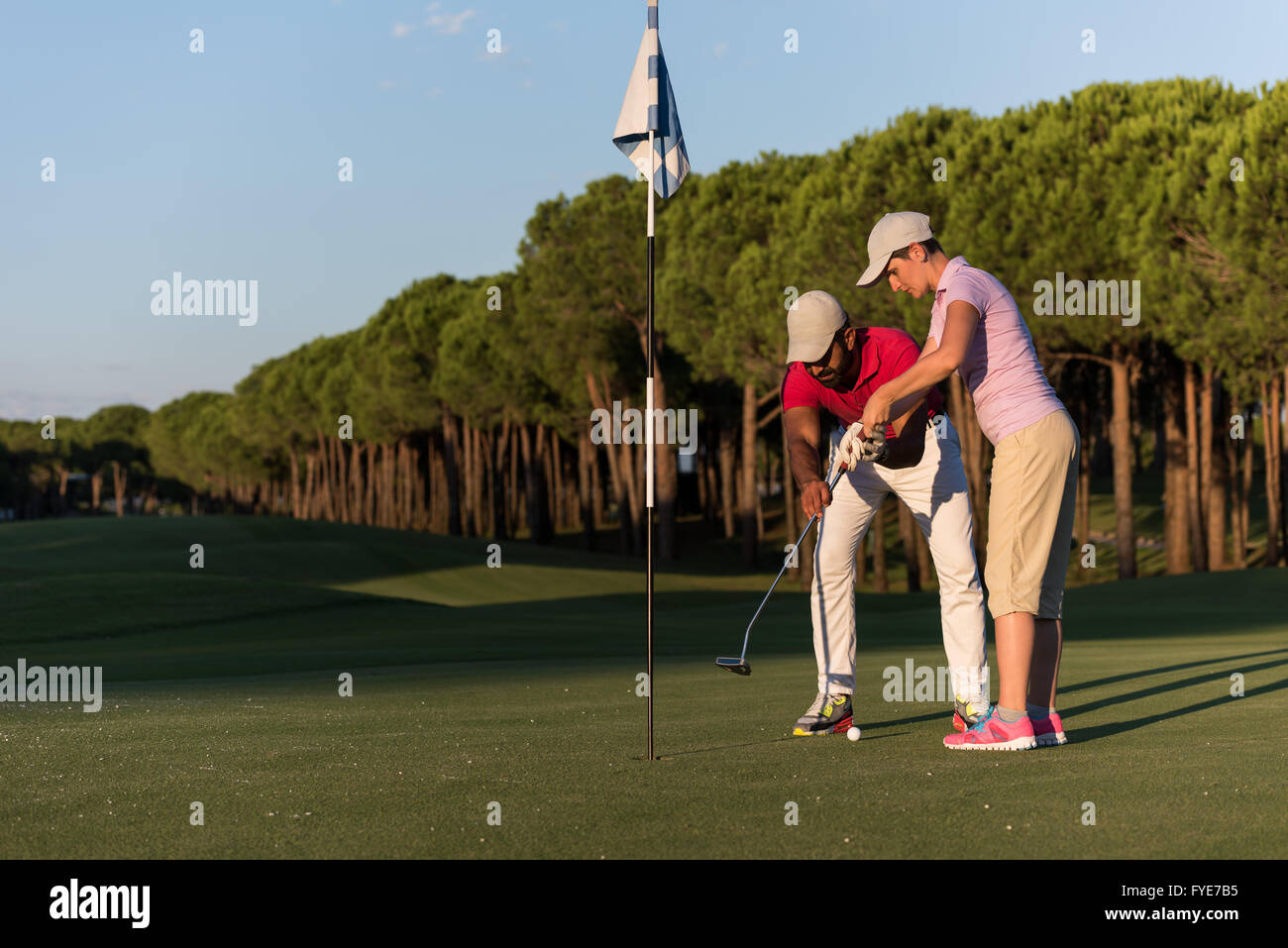 male golf instructor teaching female golf player, personal trainer ...