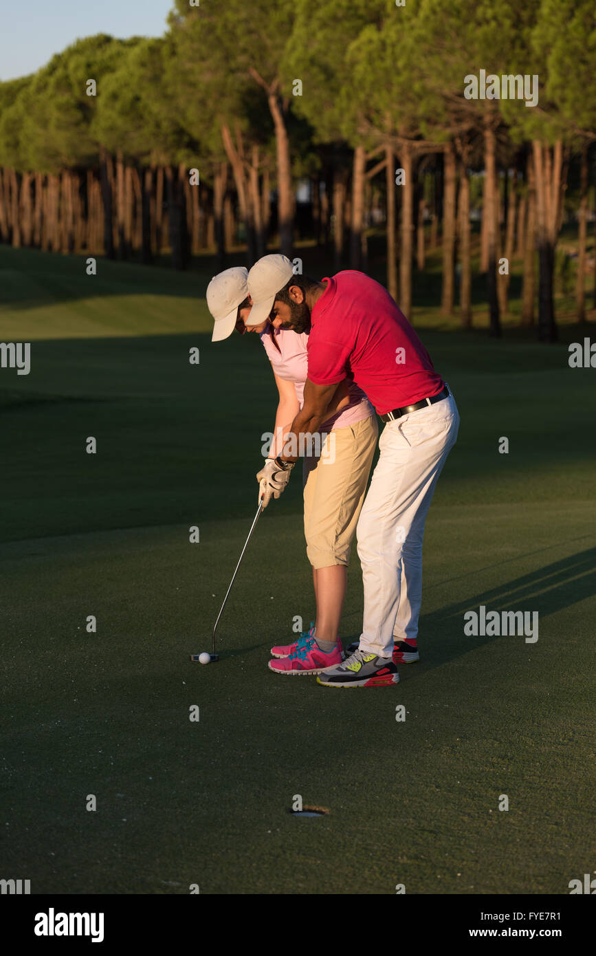 male golf instructor teaching female golf player, personal trainer ...