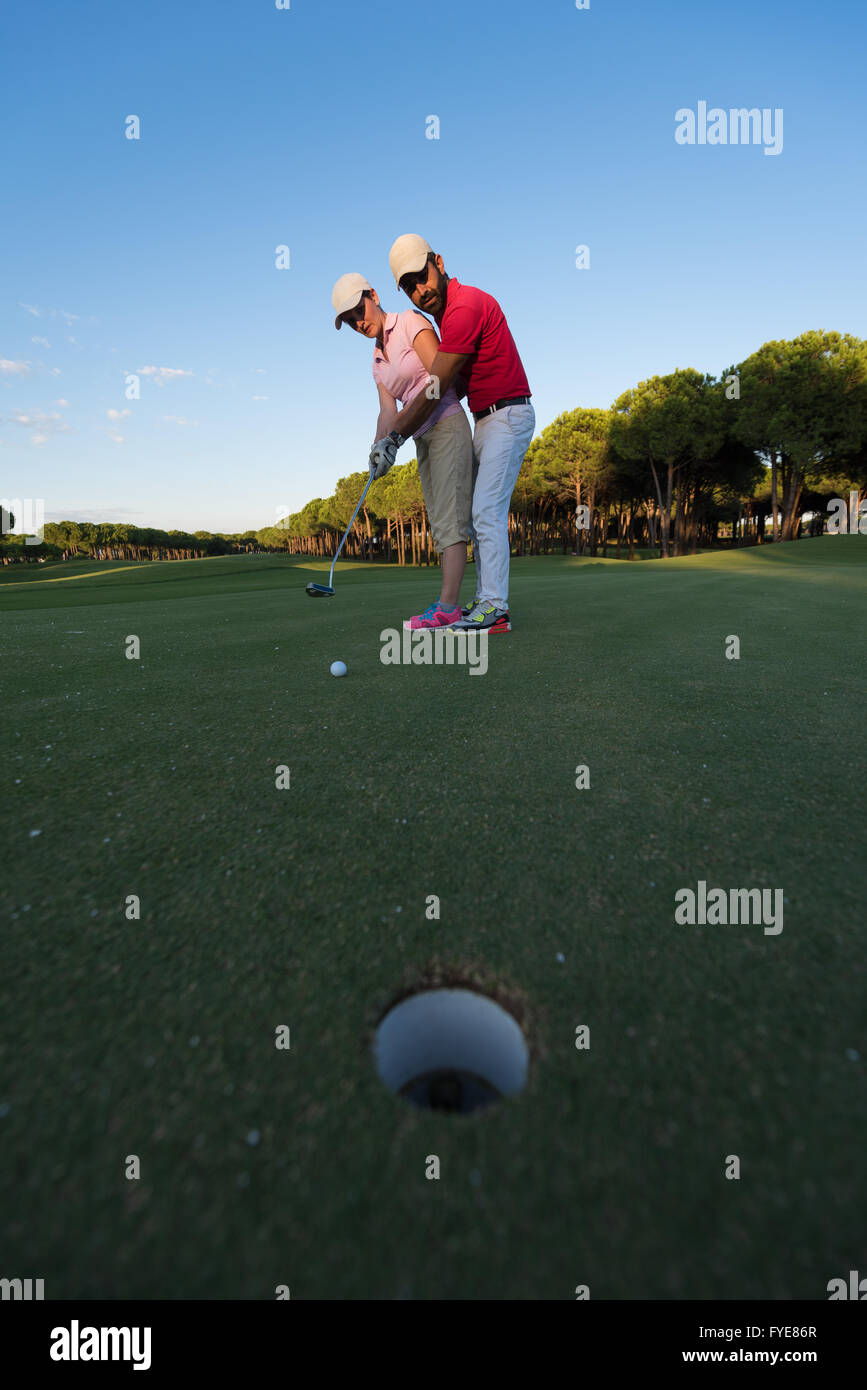 male golf instructor teaching female golf player, personal trainer ...