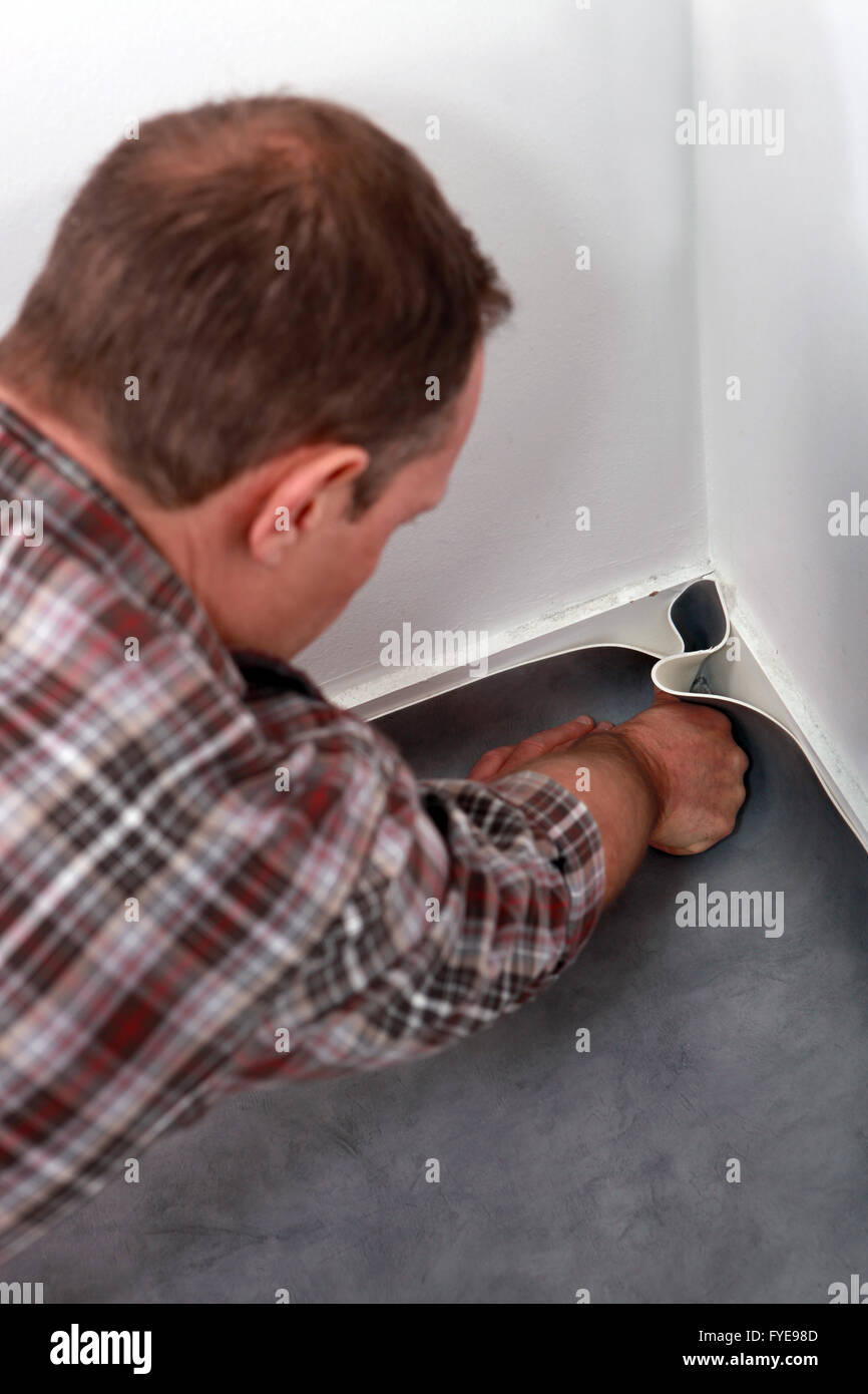 Man pushing linoleum into the corner of a room Stock Photo - Alamy