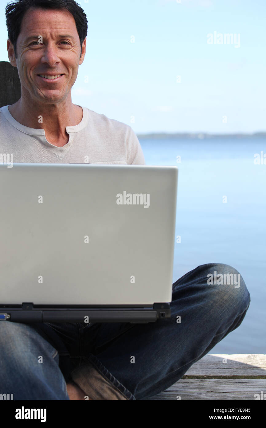 Man using a laptop computer on the waterfront Stock Photo - Alamy