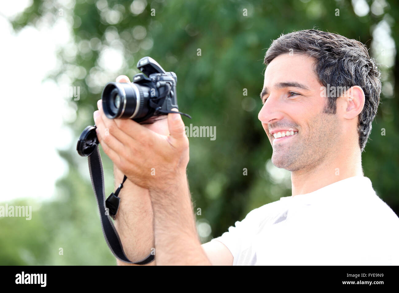 Happy relaxed man looking at the screen of his DSLR camera as he takes ...