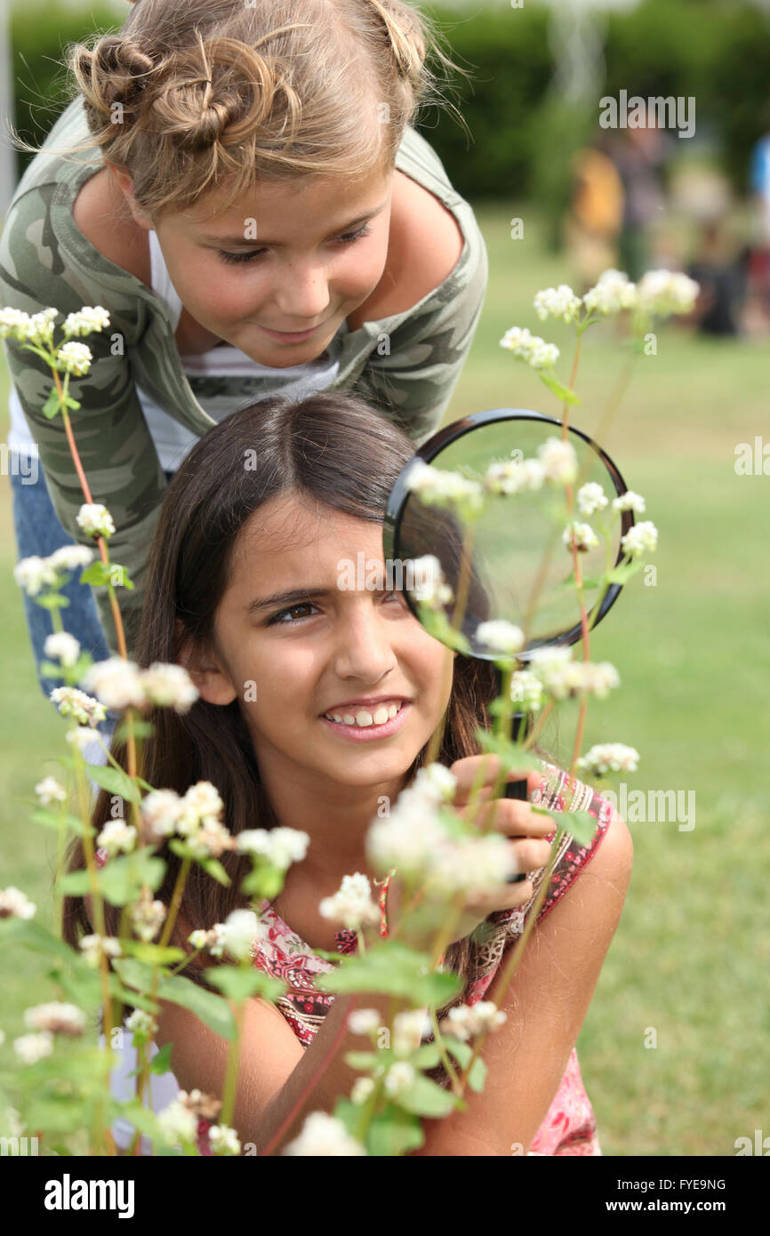 Little girls observing flowers through magnifying glass Stock Photo - Alamy