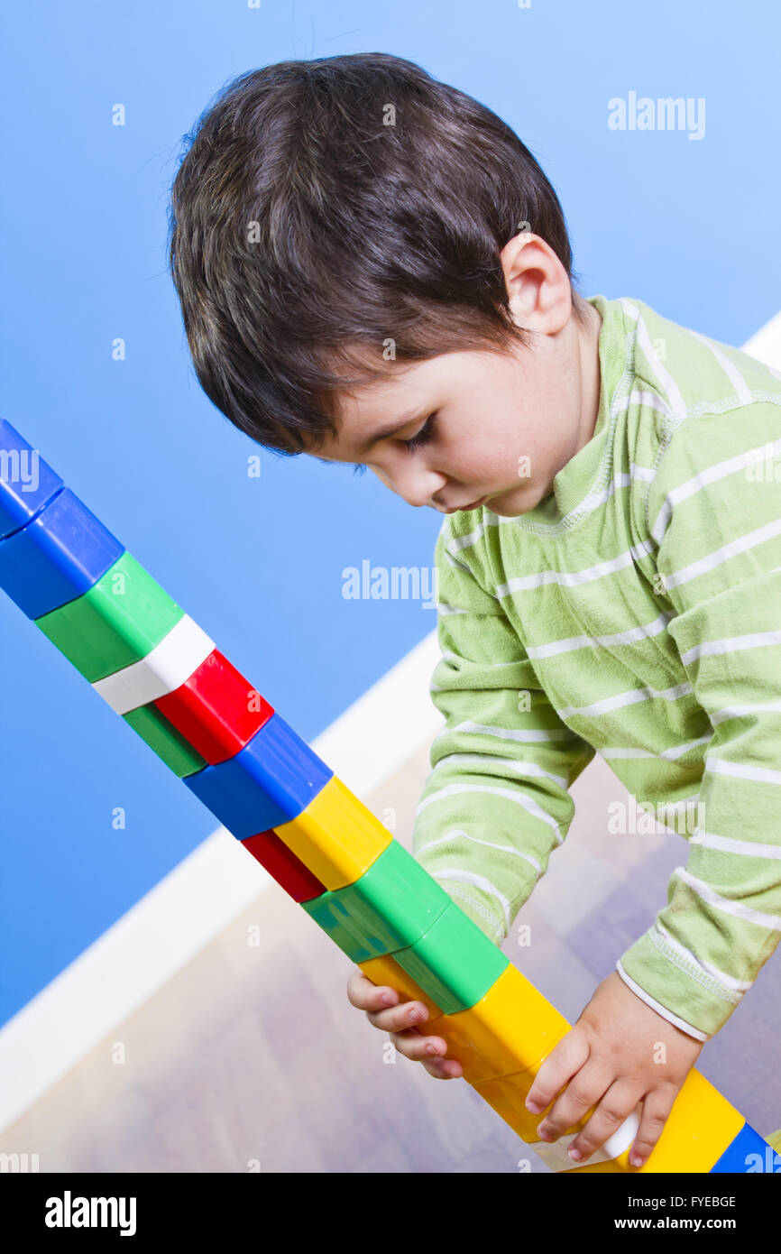 A smiling little boy is building a toy block. Wooden room Stock Photo ...