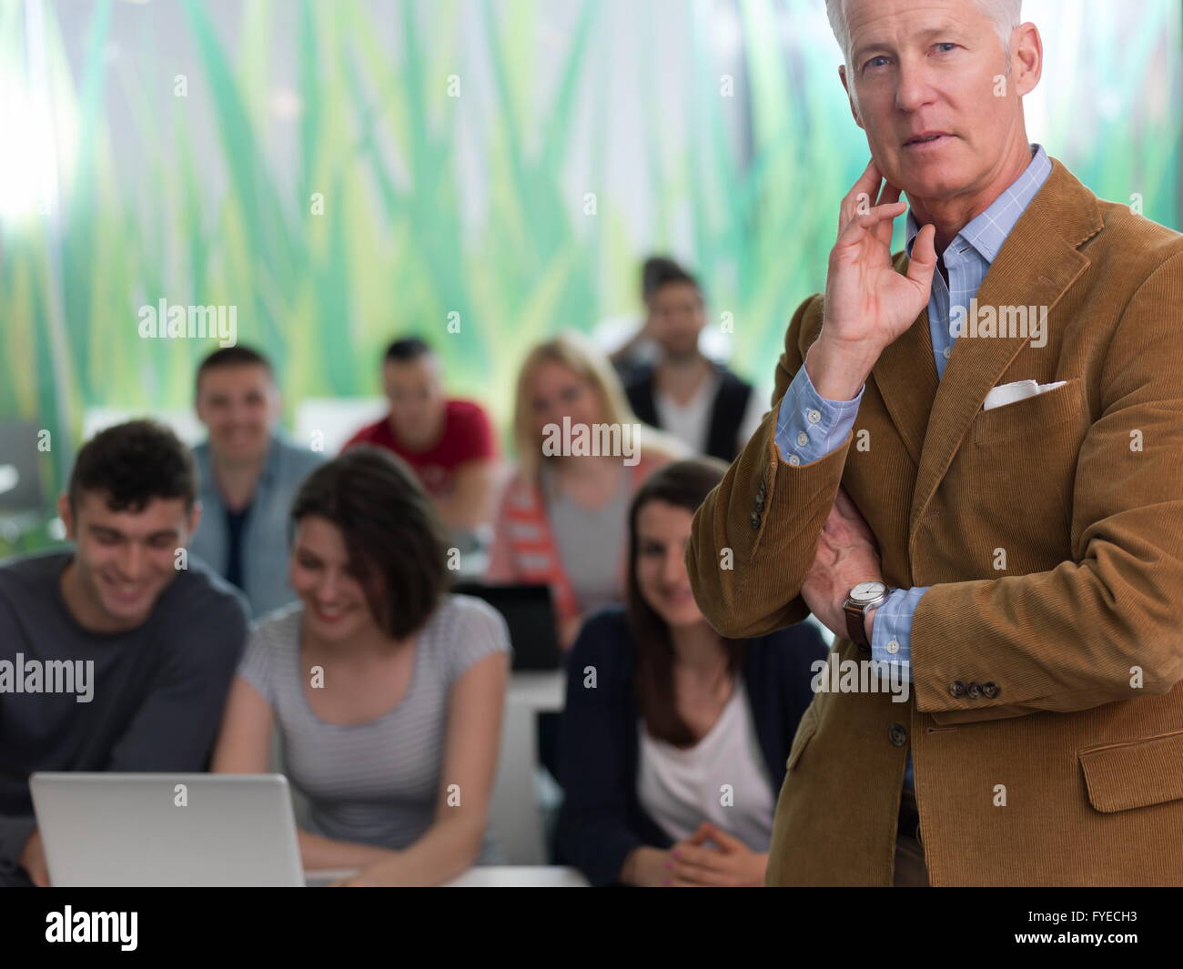 portrait of confident teacher in school classroom, students group on ...