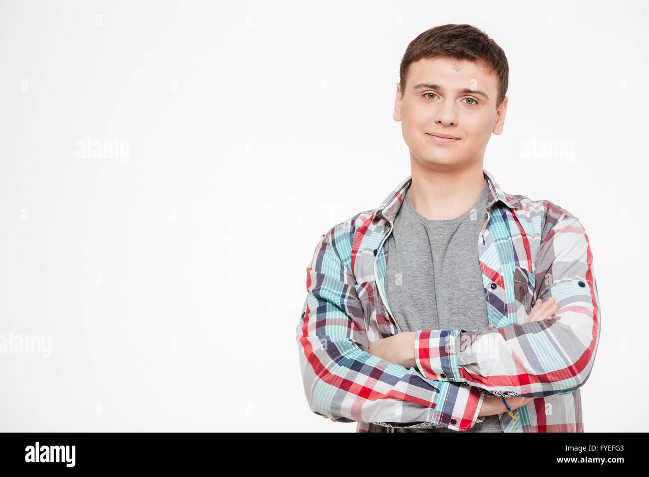 Young man standing with arm folded and looking at camera isolated on a ...