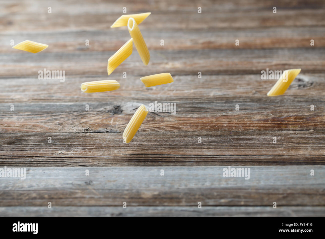 Falling penne pasta. Flying yellow raw macaroni over black background ...