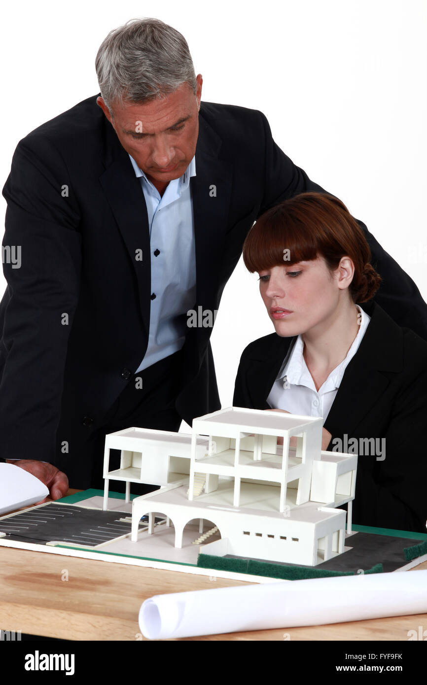 Architect and assistant looking at model house Stock Photo - Alamy