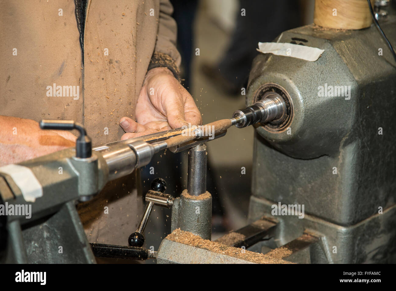 A close up of a woodturner at work using a hand cutting tool on a ...