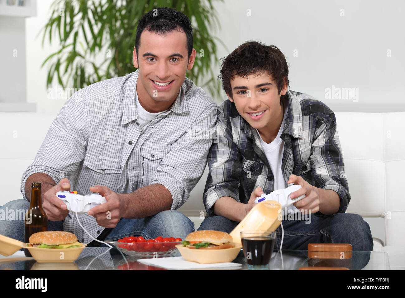 Father and son playing video games and eating junk-food Stock Photo - Alamy