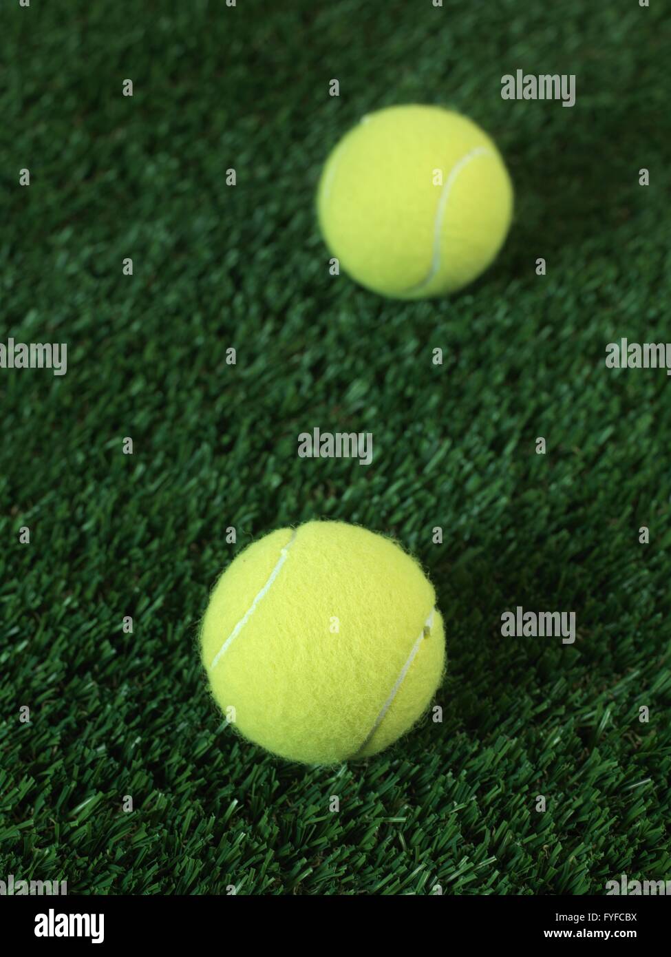 Sporting tennis balls on artificial green grass Stock Photo - Alamy
