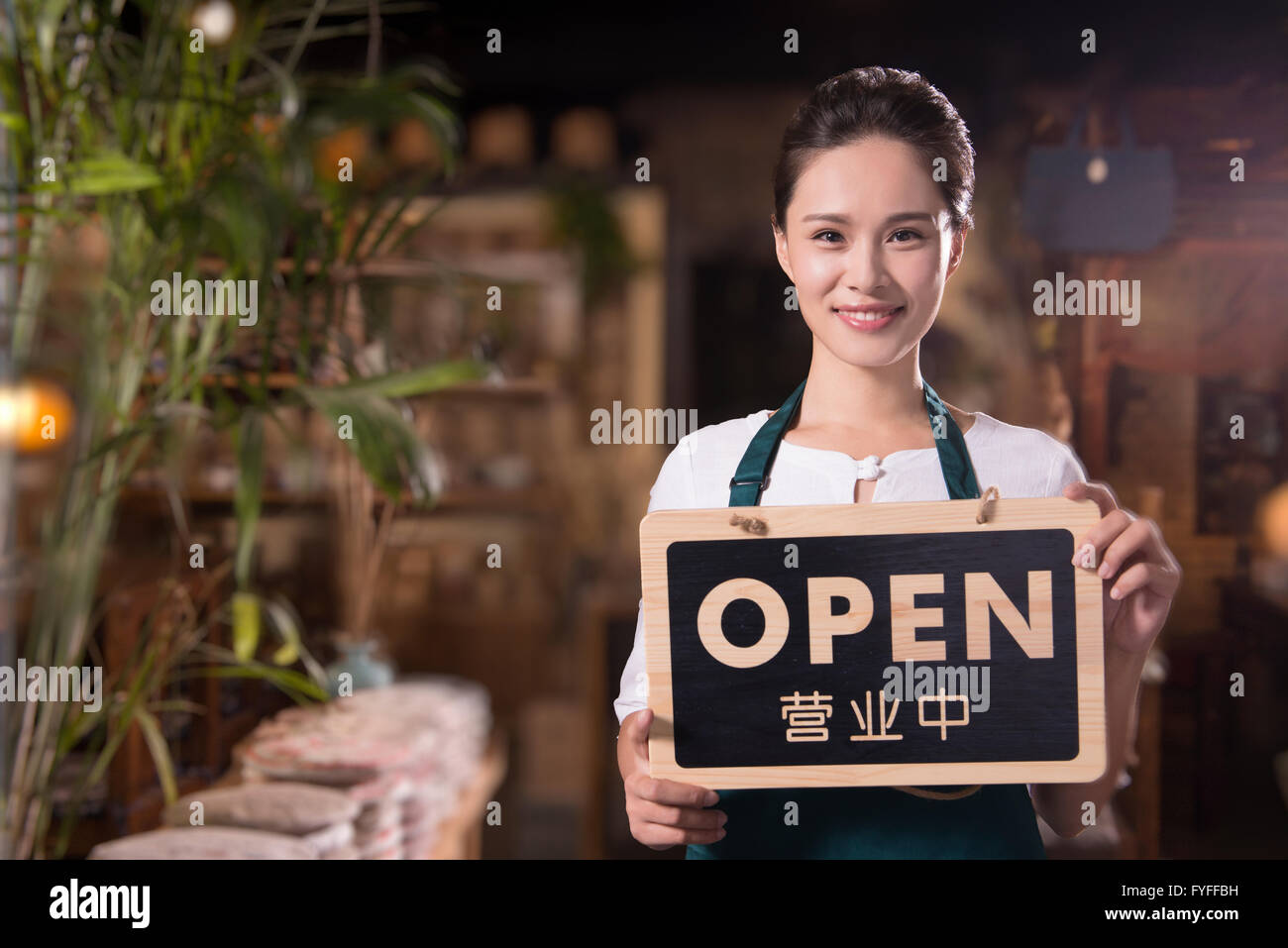 Tea house owner holding open sign Stock Photo - Alamy