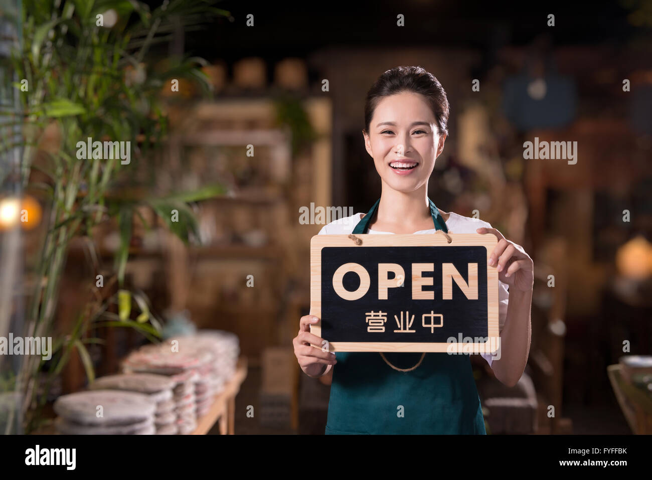 Tea house owner holding open sign Stock Photo - Alamy