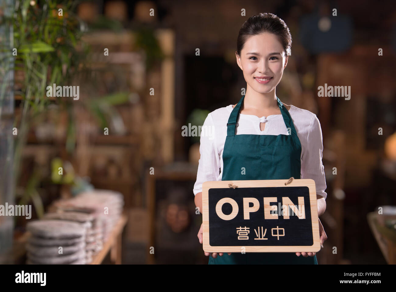 Tea house owner holding open sign Stock Photo - Alamy