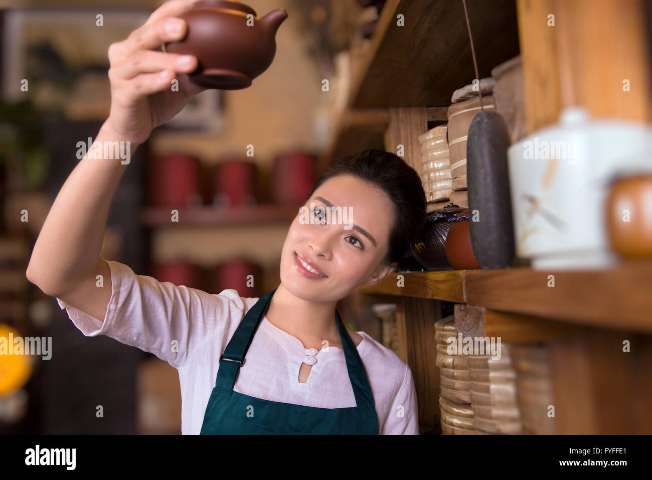 Tea house owner examining teapot Stock Photo - Alamy