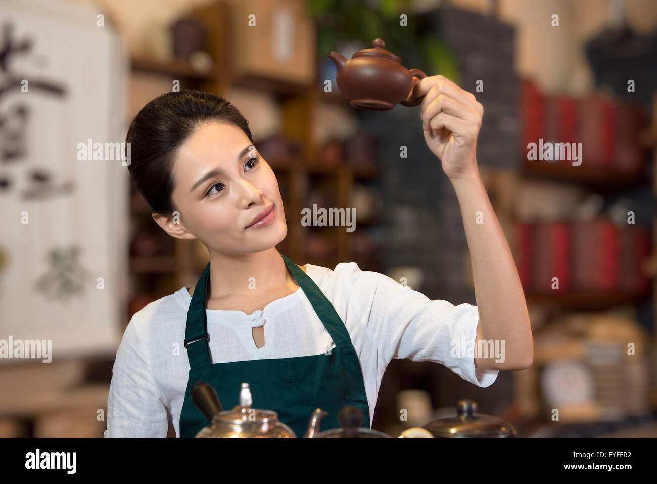 Tea house owner examining teapot Stock Photo - Alamy