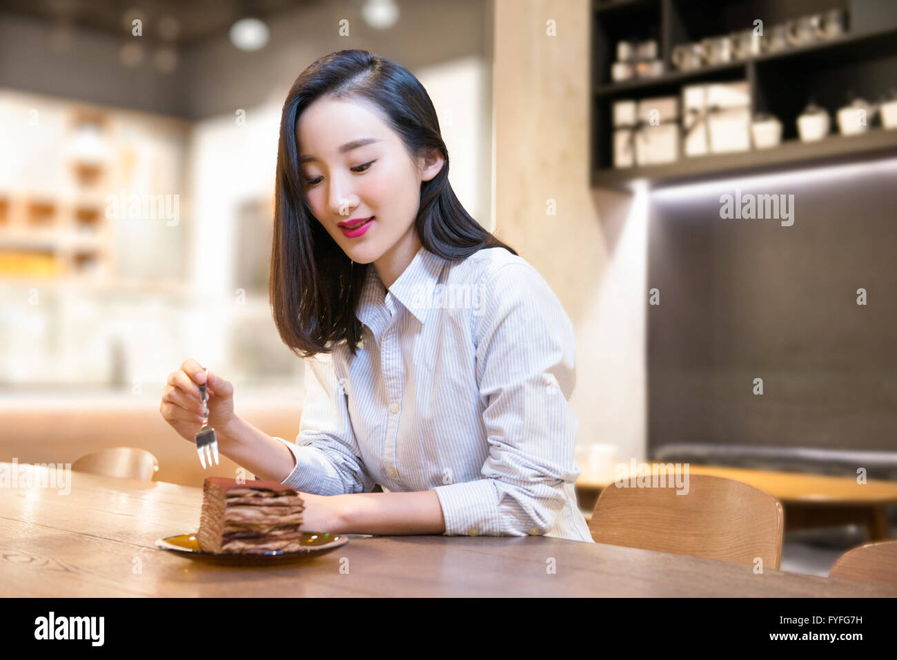 Woman eating cake in bakery Stock Photo - Alamy