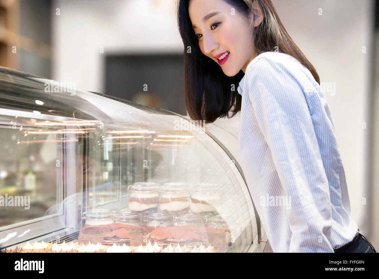 Young woman choosing cake in bakery Stock Photo - Alamy