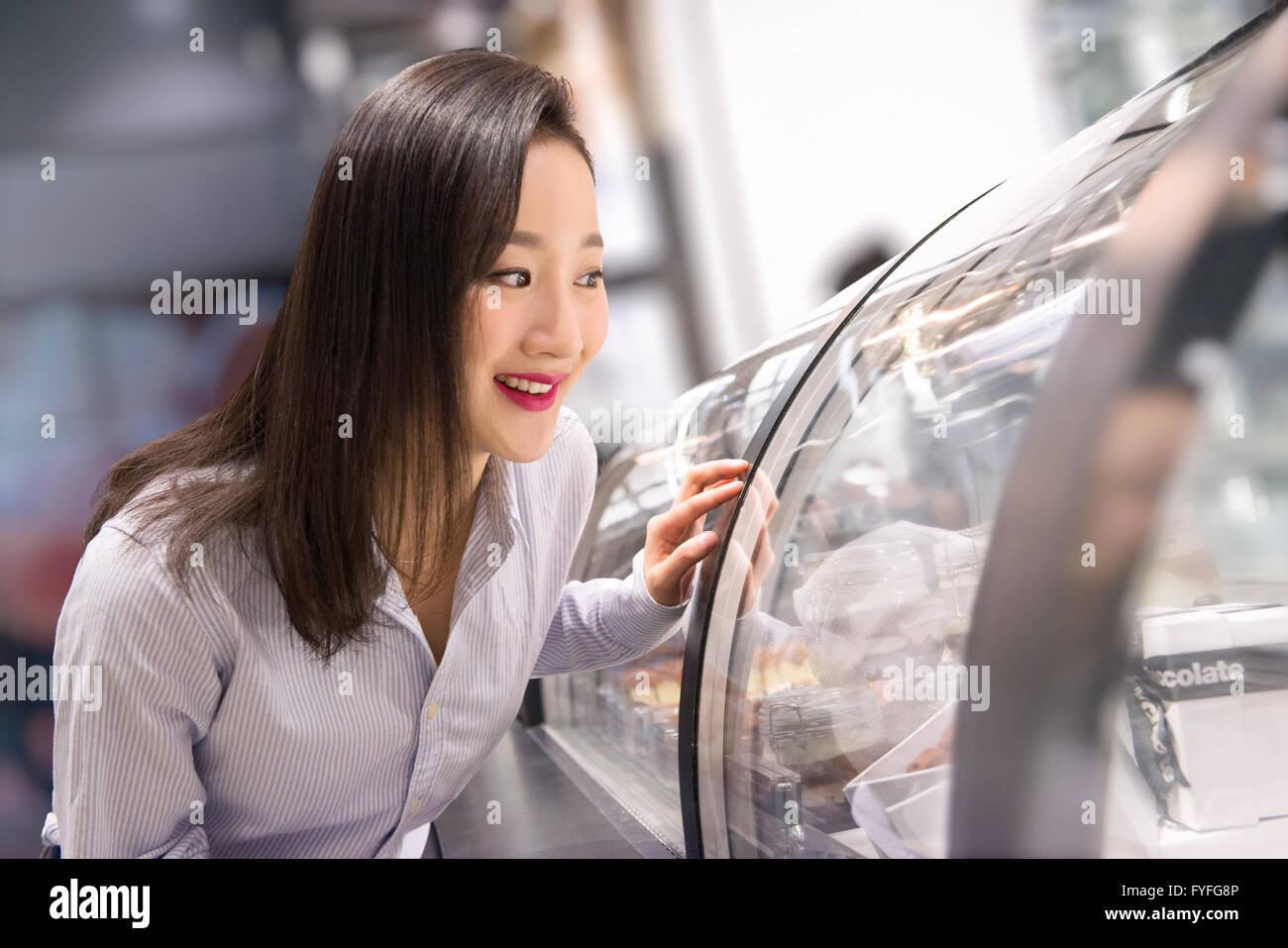 Young woman choosing cake in bakery Stock Photo - Alamy