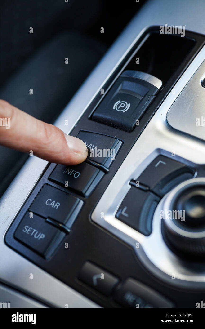 Vertical shot of a navigation system button in a car, and a finger ...