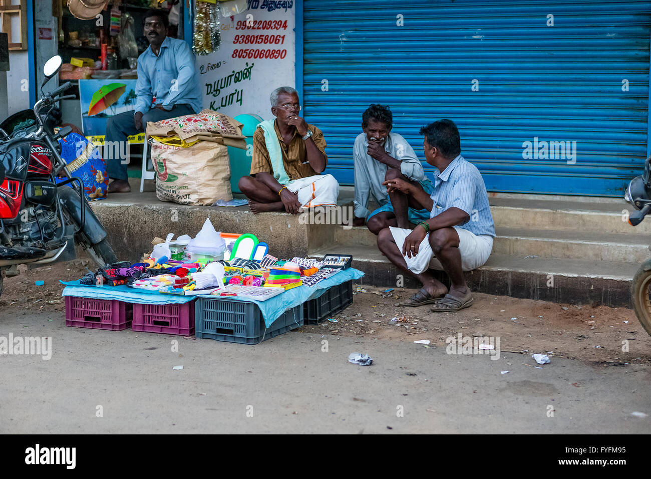 Three men sitting on steps trying to sell goods at the side of the ...