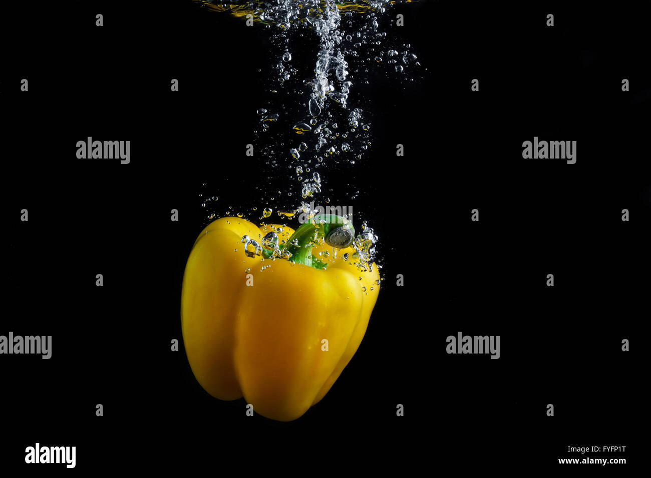 Fresh paprika splash in water with air bubbles. Yellow paprika in water ...