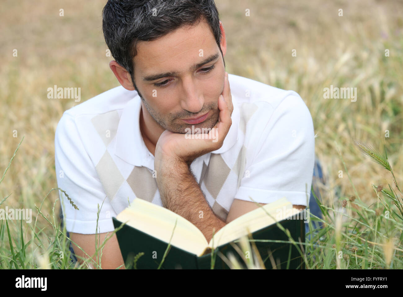 young man lying on the grass and reading a book Stock Photo - Alamy