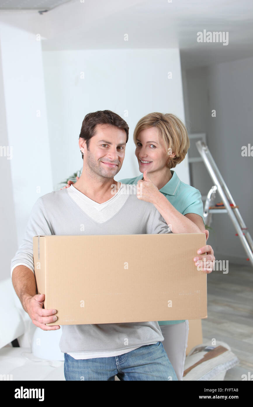 Woman giving the thumbs up to her partner as they move into a new home ...