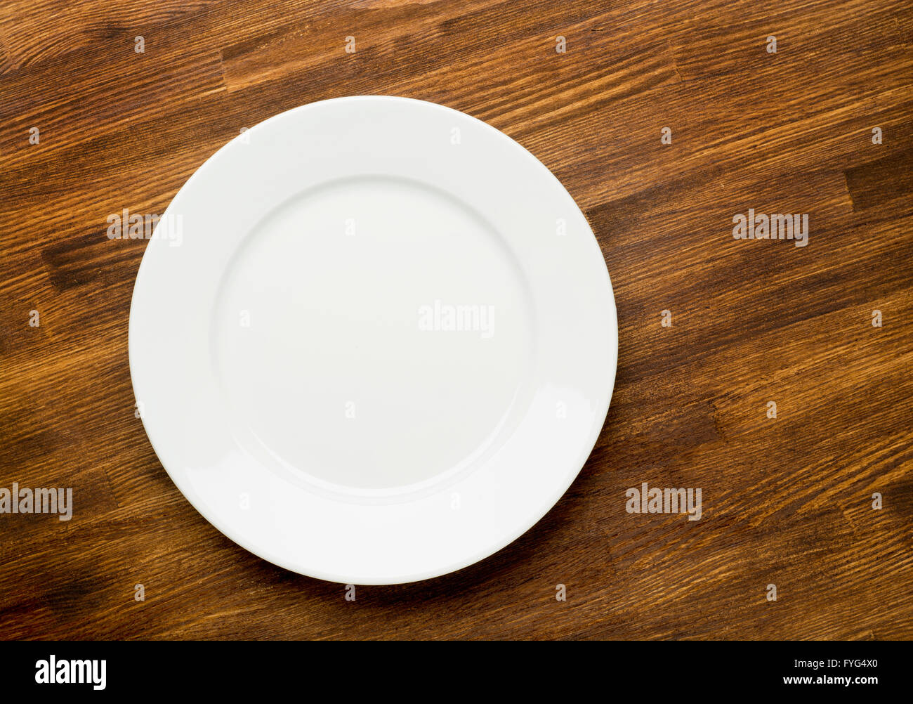 Empty white plate on wooden table top view Stock Photo - Alamy