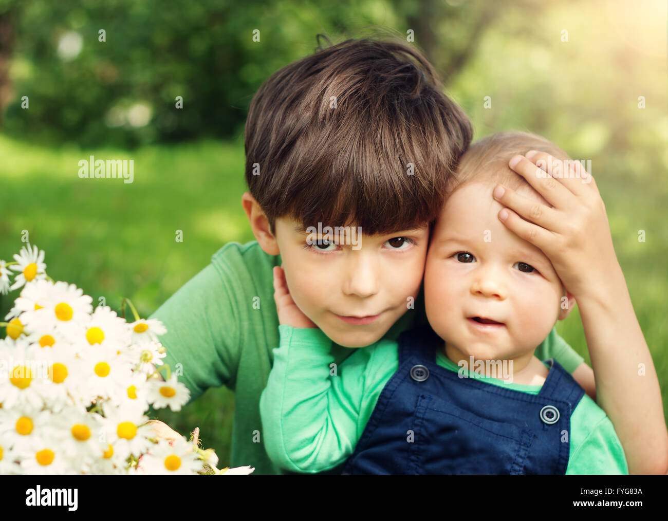 Two lovely brothers sitting in park with flowers Stock Photo - Alamy