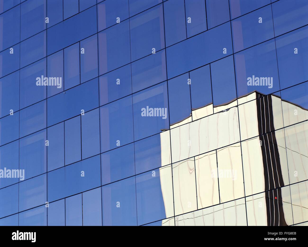 Reflections of white office building in glass-fronted building in ...