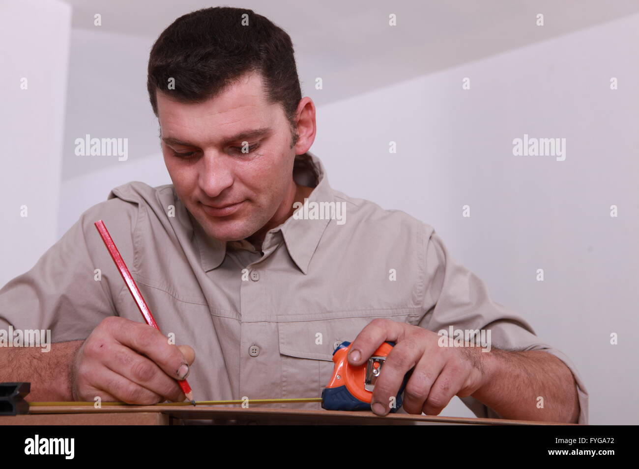 Tradesman marking a measurement with a pencil Stock Photo - Alamy