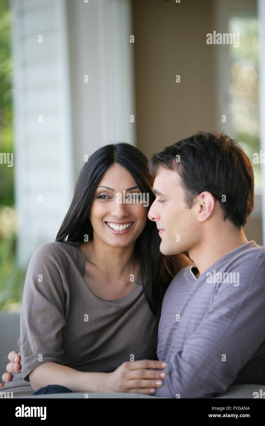 Couple cuddling up to each other on the sofa Stock Photo - Alamy