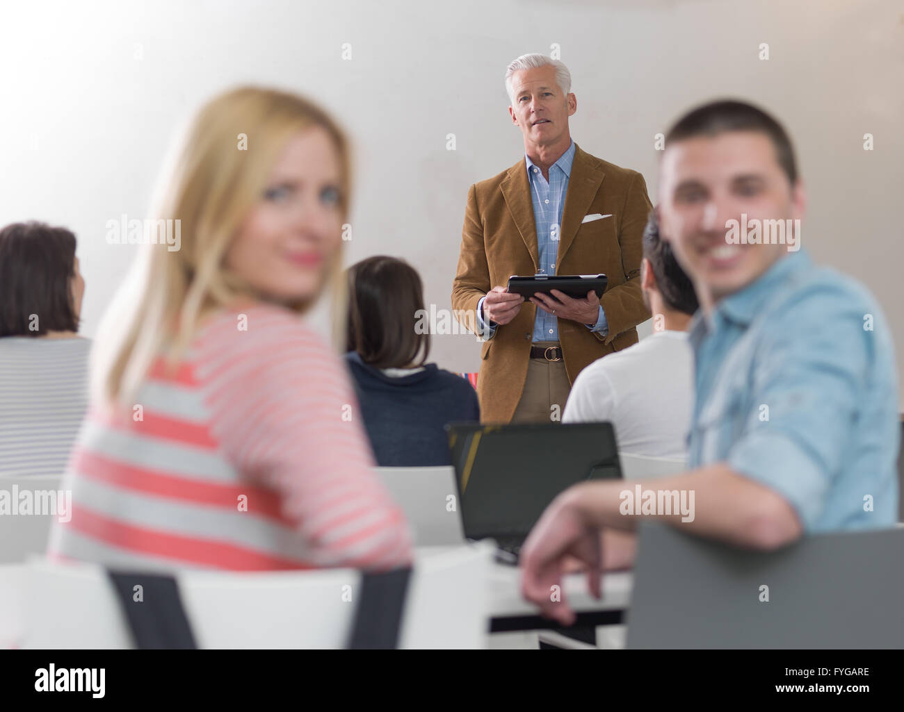 senior teacher with group of happy students in modern school classroom ...