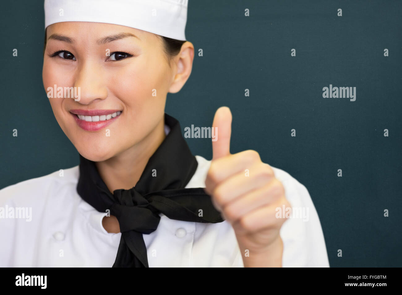 Portrait of a smiling female cook gesturing thumbs up in the kitchen ...