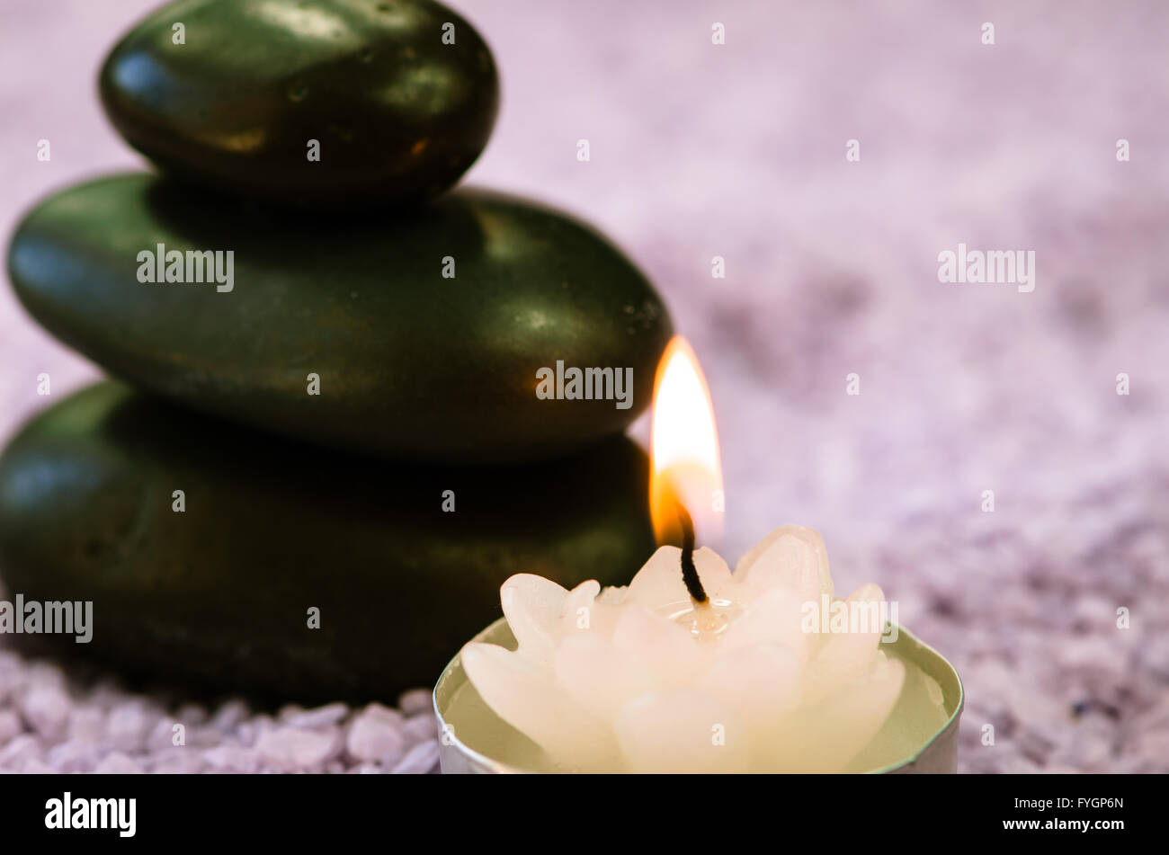 pile of black lava stones and burning candle Stock Photo - Alamy