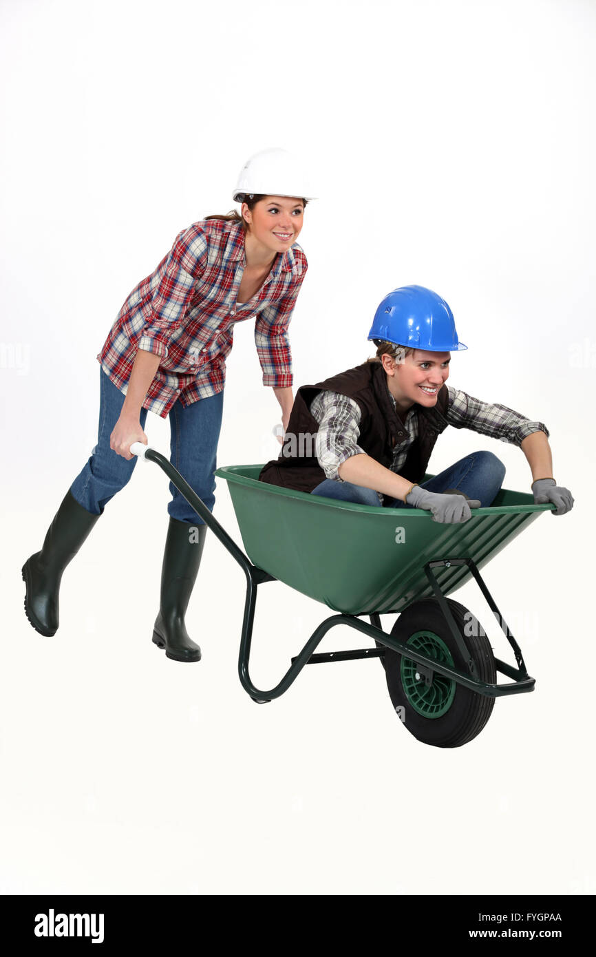Two female construction workers racing in a wheelbarrow Stock Photo - Alamy