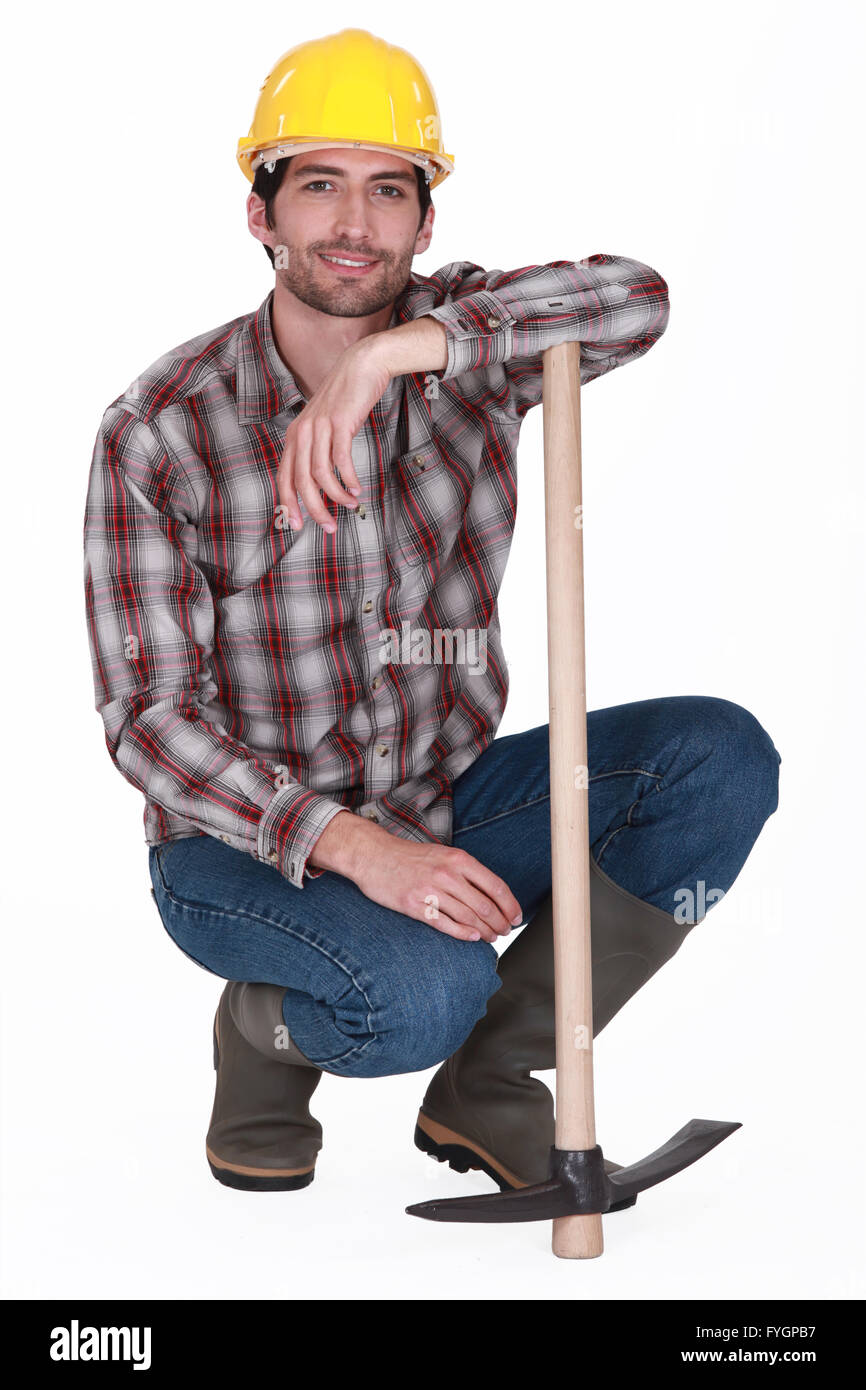 handsome bricklayer with arm resting on pickaxe Stock Photo - Alamy