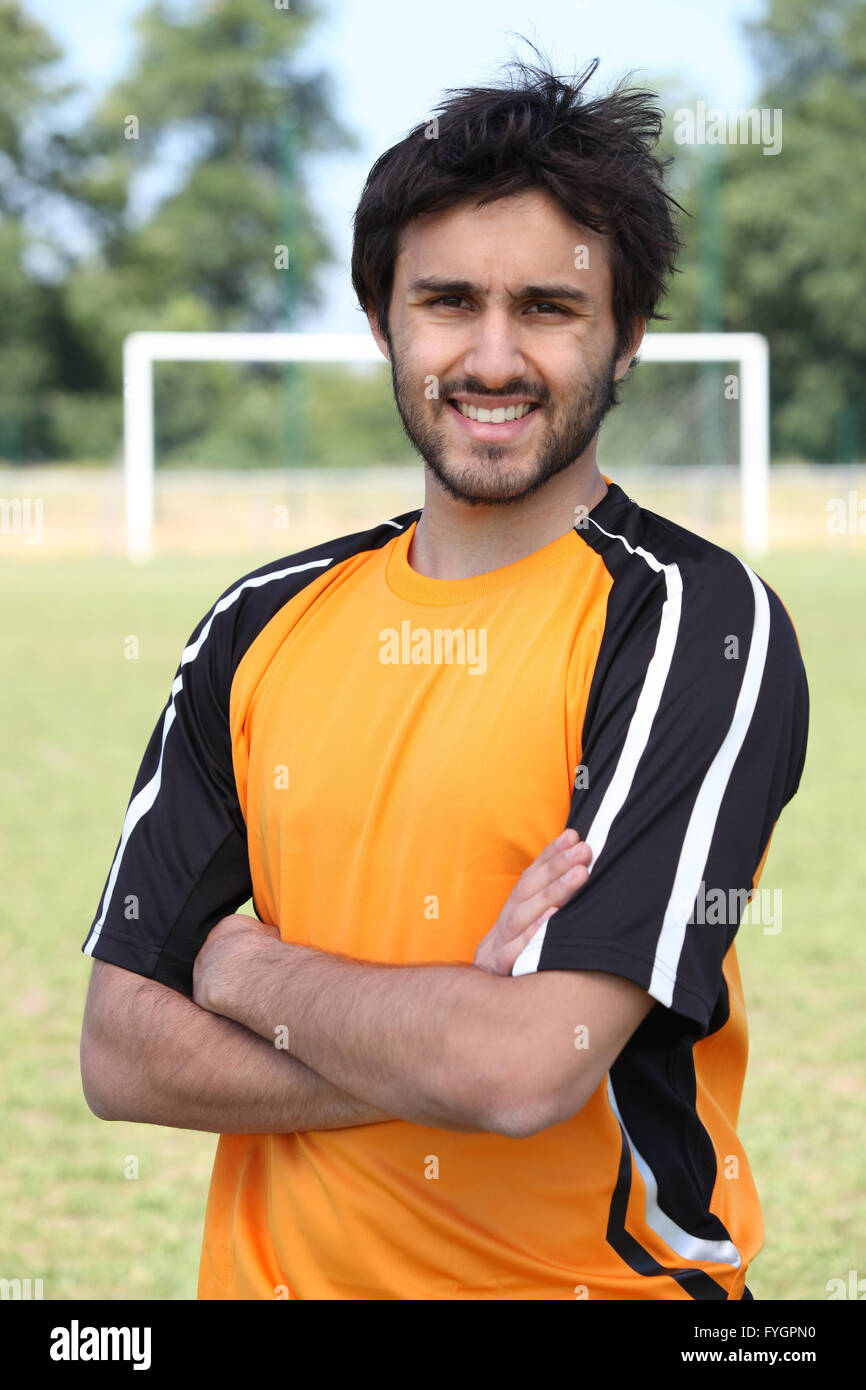 Footballer with arms crossed standing on pitch with goal in the ...