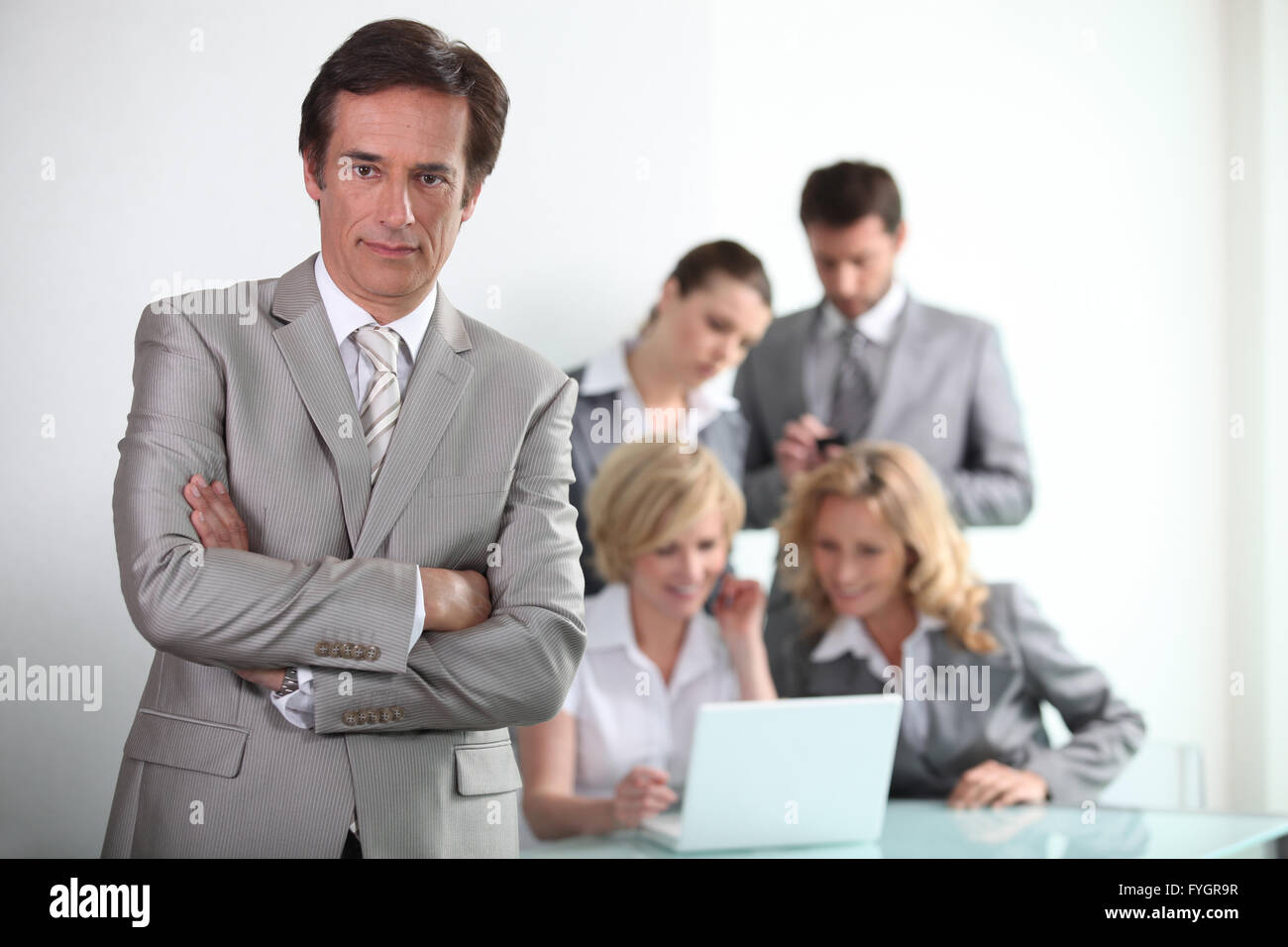 Confident male executive with his team of colleagues in the background ...