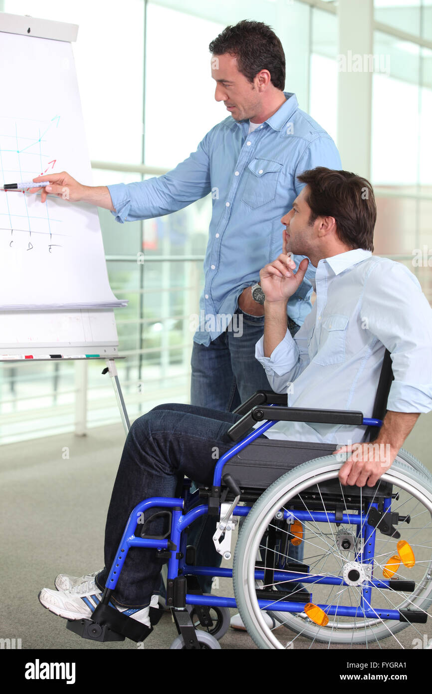 An employee pointing at a board and explaining something to a male ...