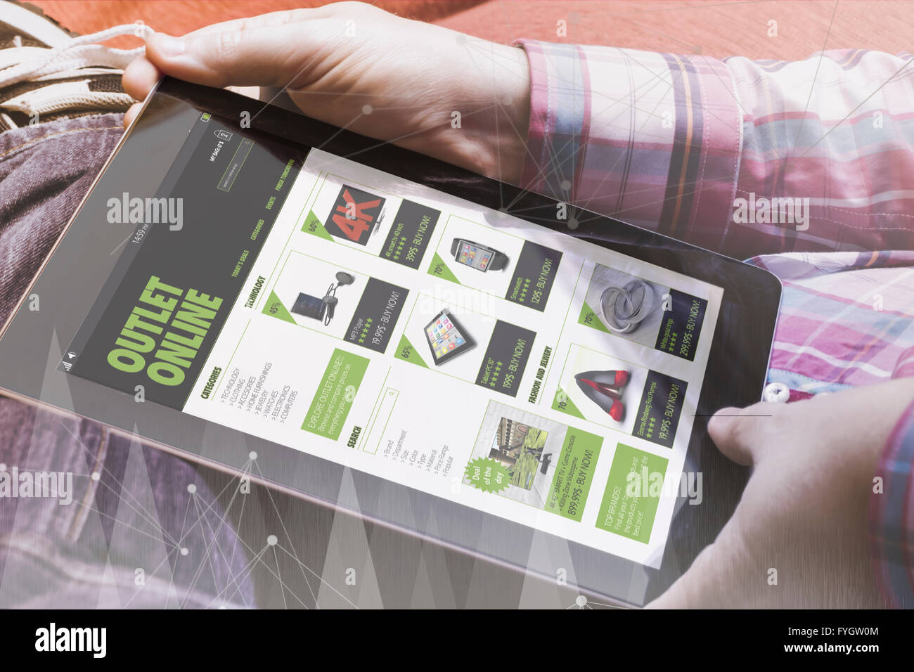 close-up view of man holding a tablet showing outlet online site ...