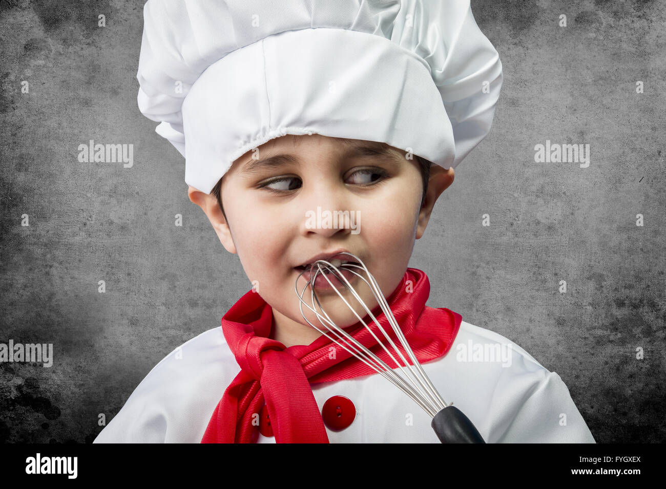 Little boy cook in uniform over vintage background playing with ...