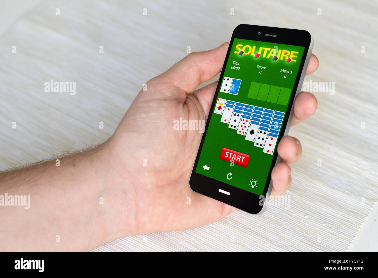 Close up of hand holding mobile smart phone with cards game app on the ...